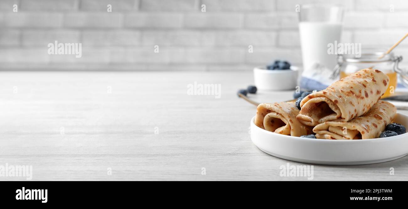 Delicious crepes with blueberries on white wooden table, space for text ...