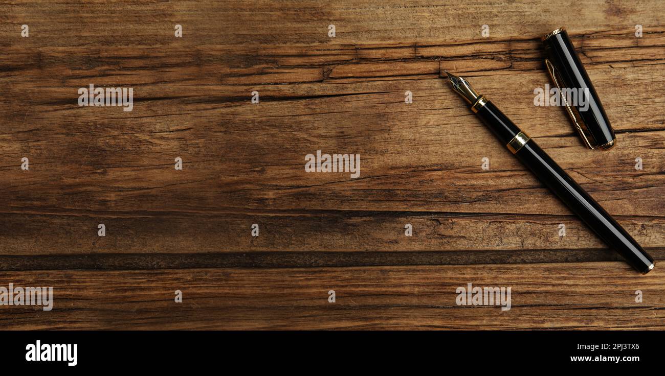 Beautiful fountain pen on wooden table, top view with space for text ...