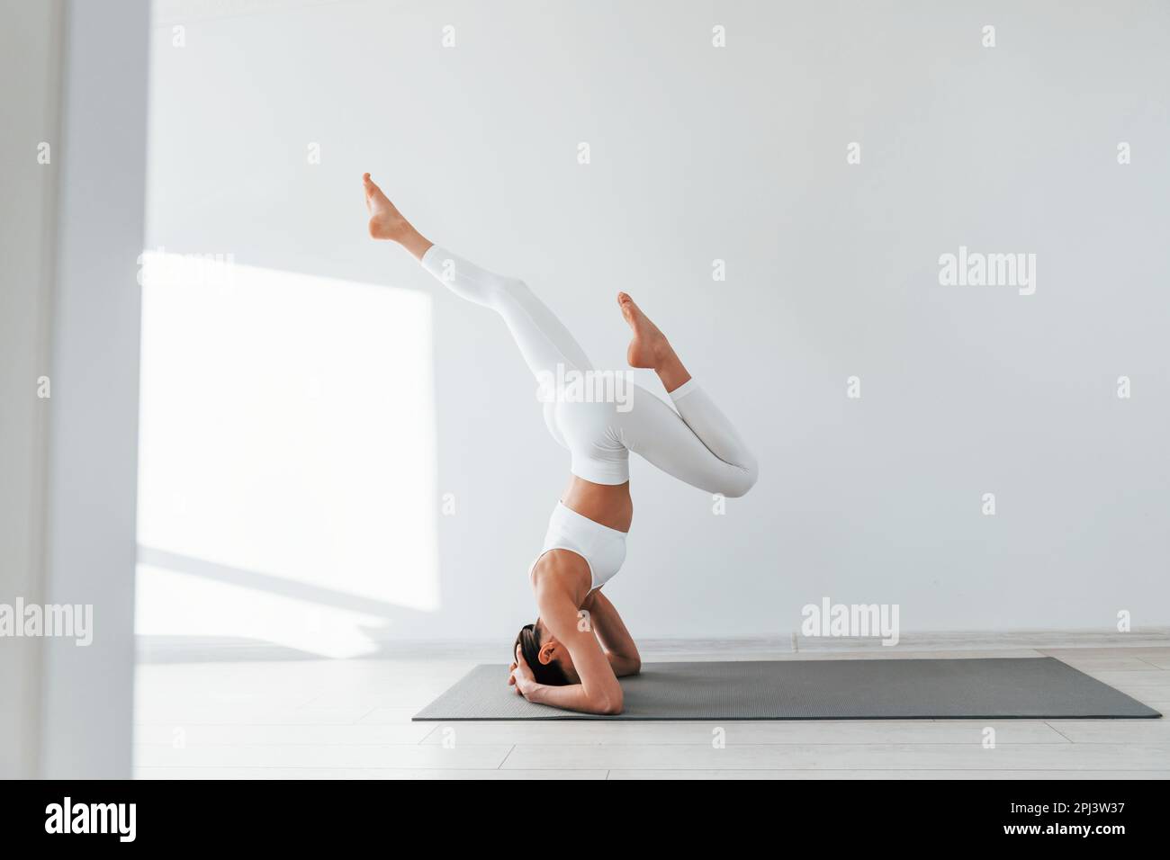 Doing exercises. Young caucasian woman with slim body shape is indoors ...