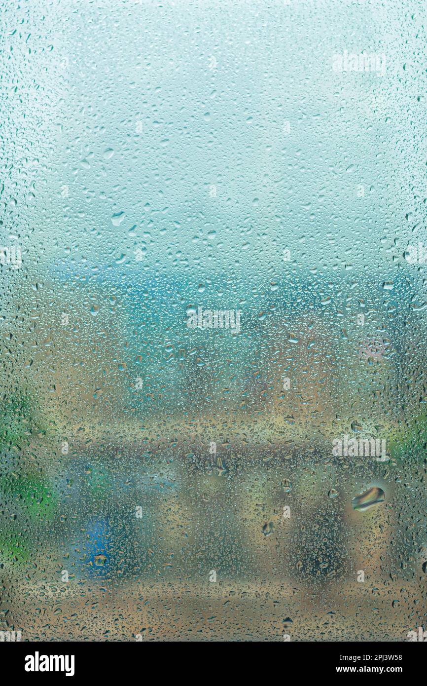 Raindrops on glass during rain, large drops. Landscape with raindrops falling on the window of ...