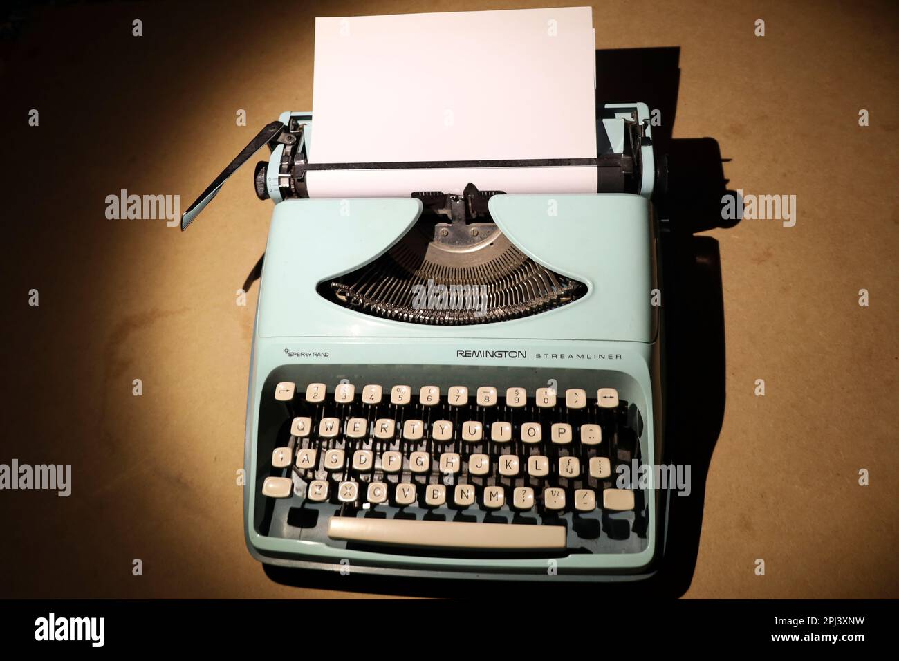 Old green typewriter Remington in light with blank page in the ...