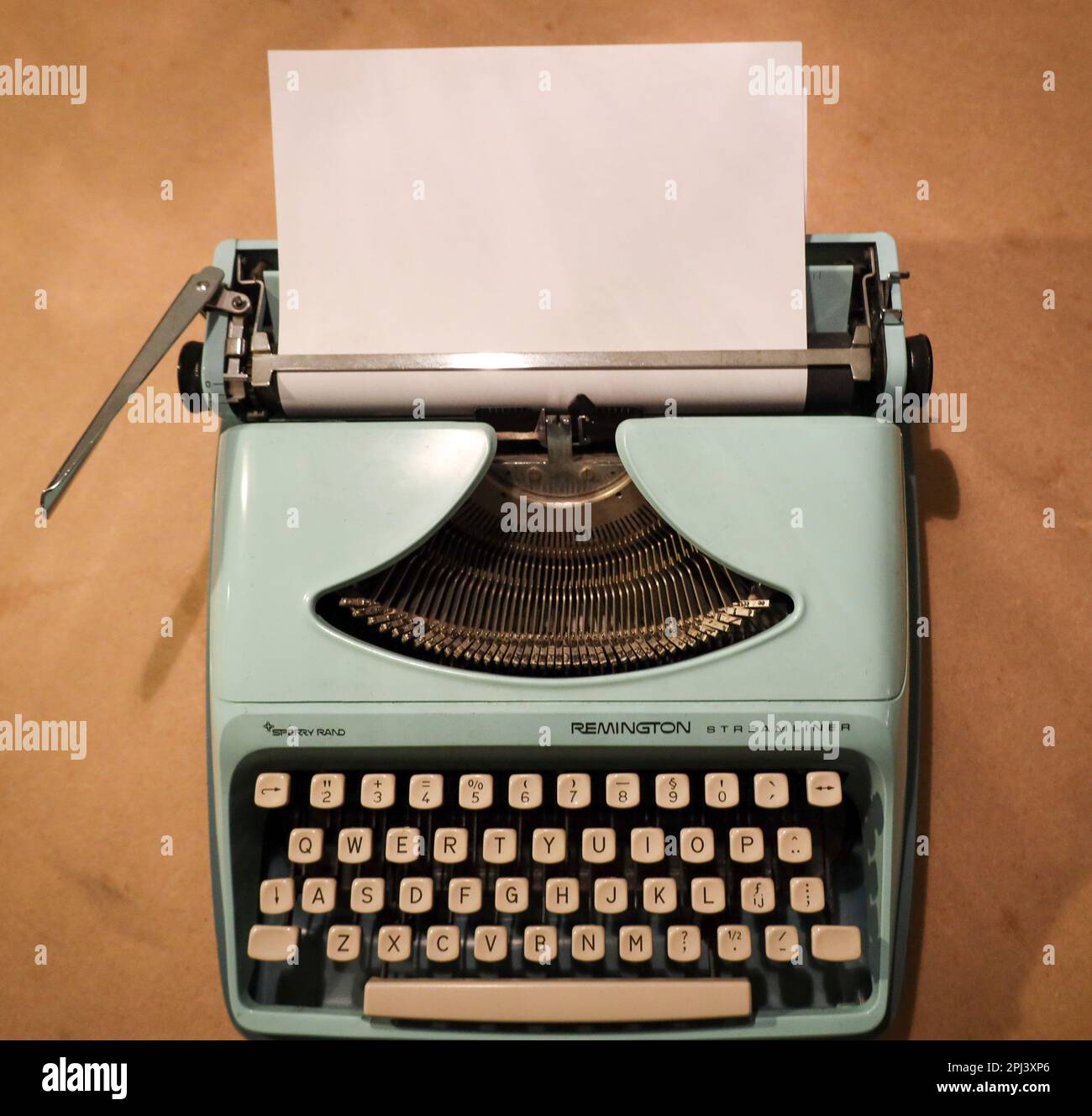 Old green typewriter Remington in light with blank page in the ...