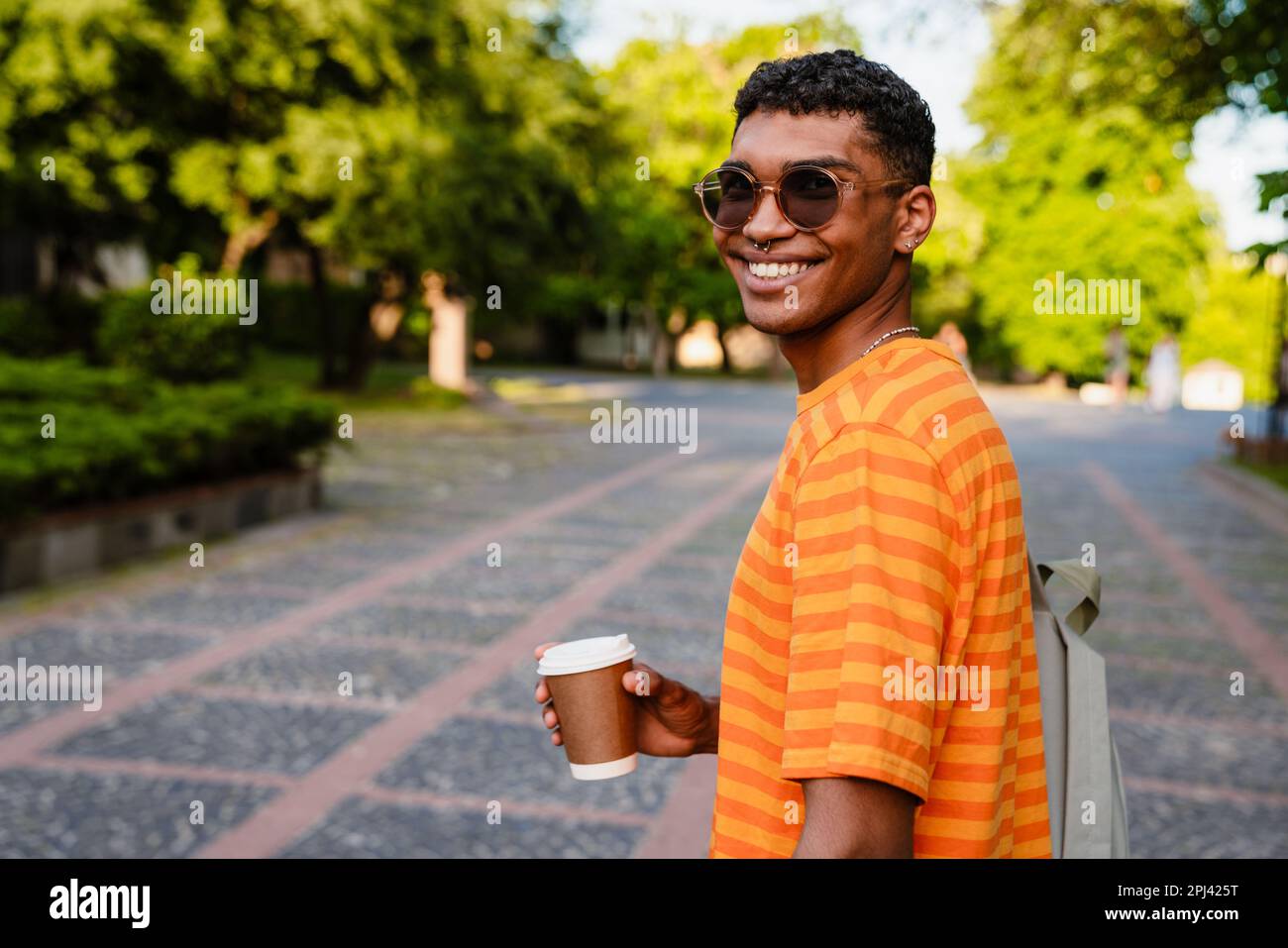 Young smiling african man student with backpack drinking coffee while ...