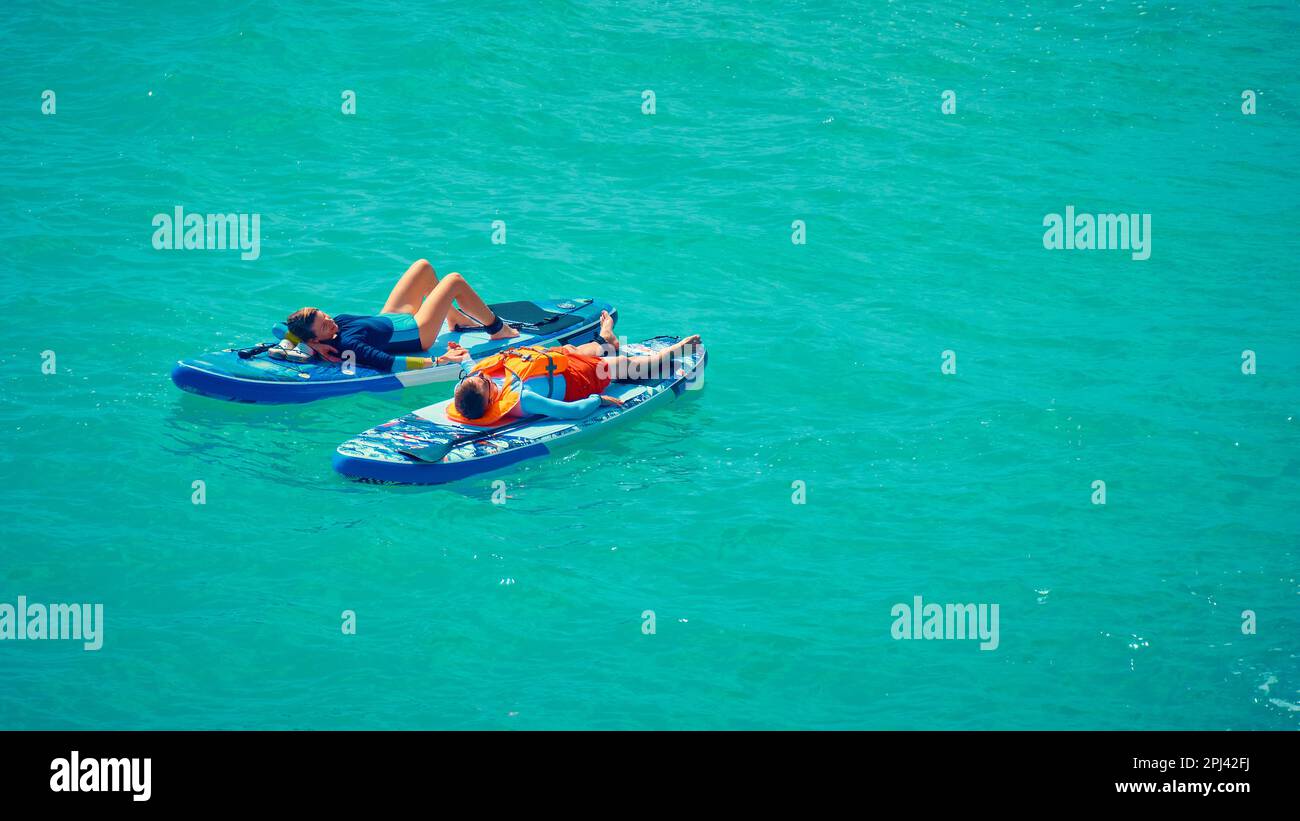 Man and woman lying down on a stand up paddle boards. Couple taking ...