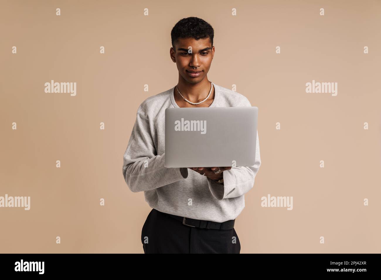 Young black man working with laptop while posing at camera isolated ...