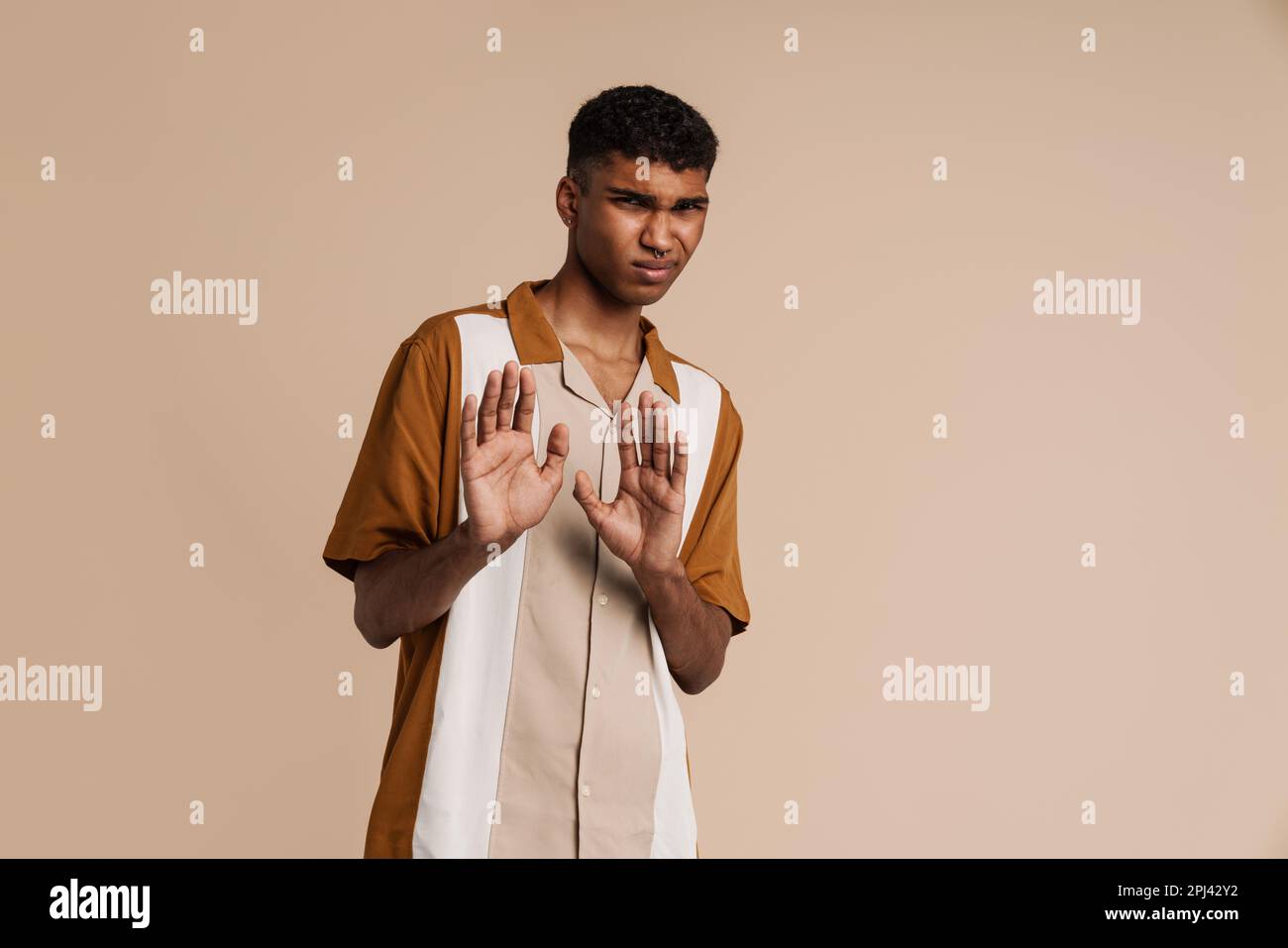 Young black man with piercing frowning while making stop gesture ...