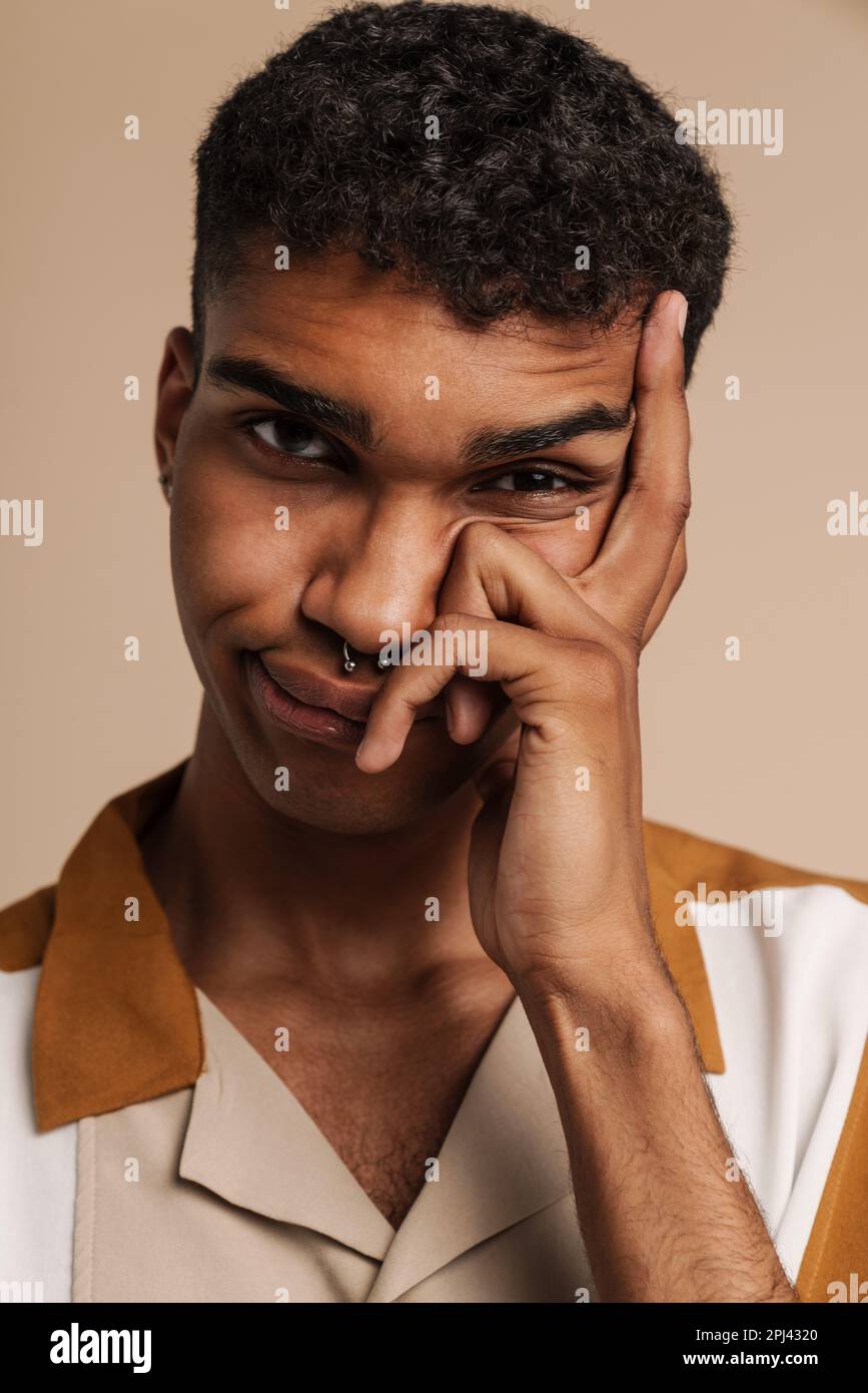 Young black man with piercing frowning while propping up his head ...