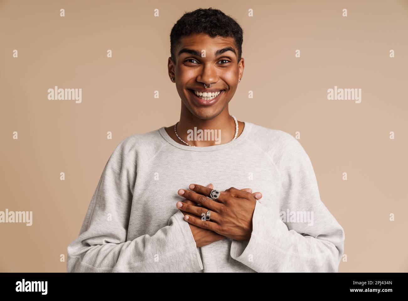 Young black man smiling while holding hands on his chest isolated over ...