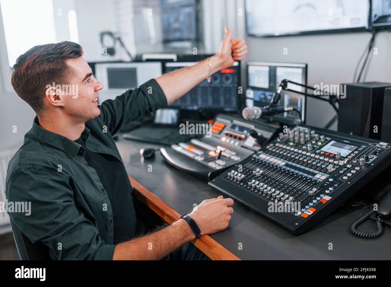 Setting the equipment. Young man is indoors in the radio studio is busy ...
