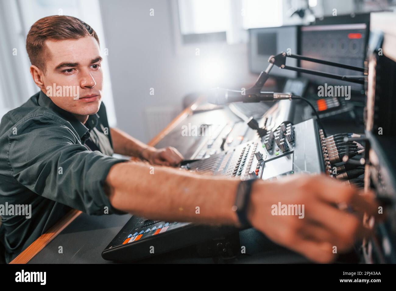 Setting the equipment. Young man is indoors in the radio studio is busy ...