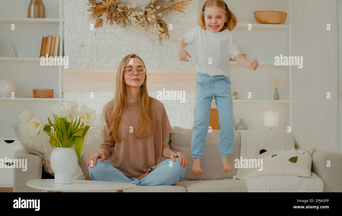 Mindful calm Caucasian mother in glasses meditating sitting on sofa ...