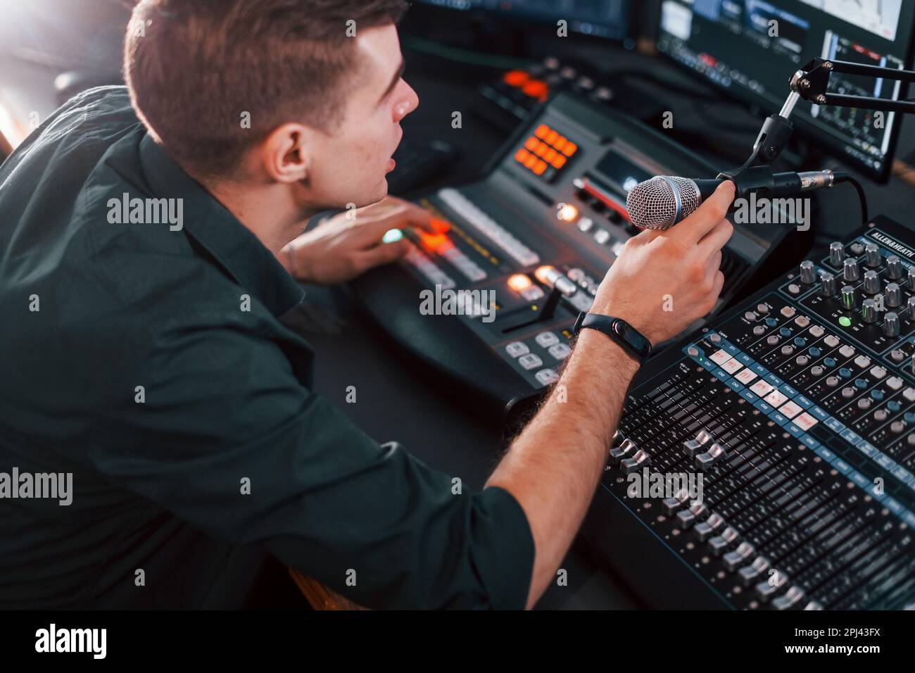 Setting the equipment. Young man is indoors in the radio studio is busy ...