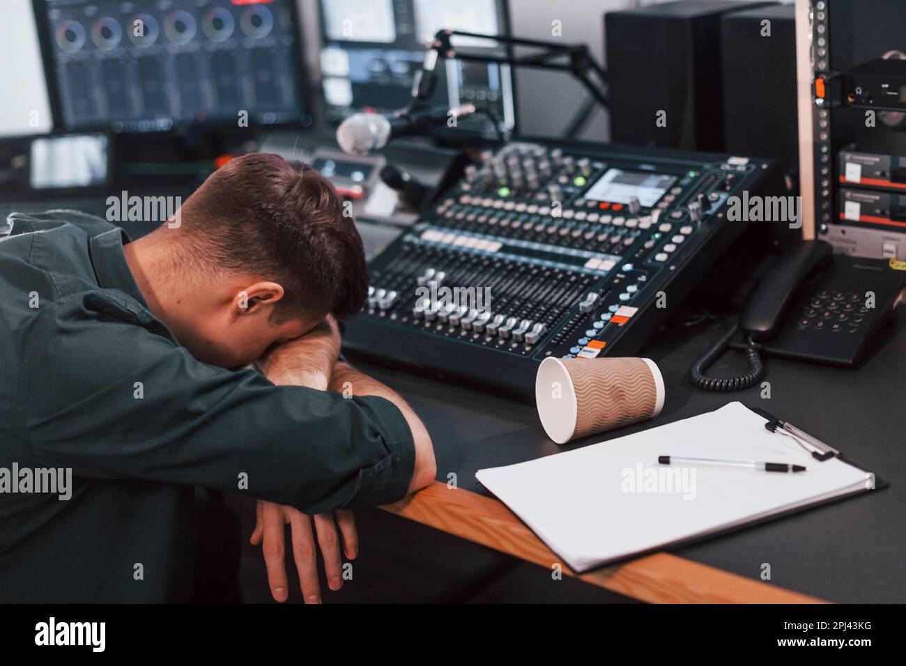 Tired by work. Young man is indoors in the radio studio is busy by ...