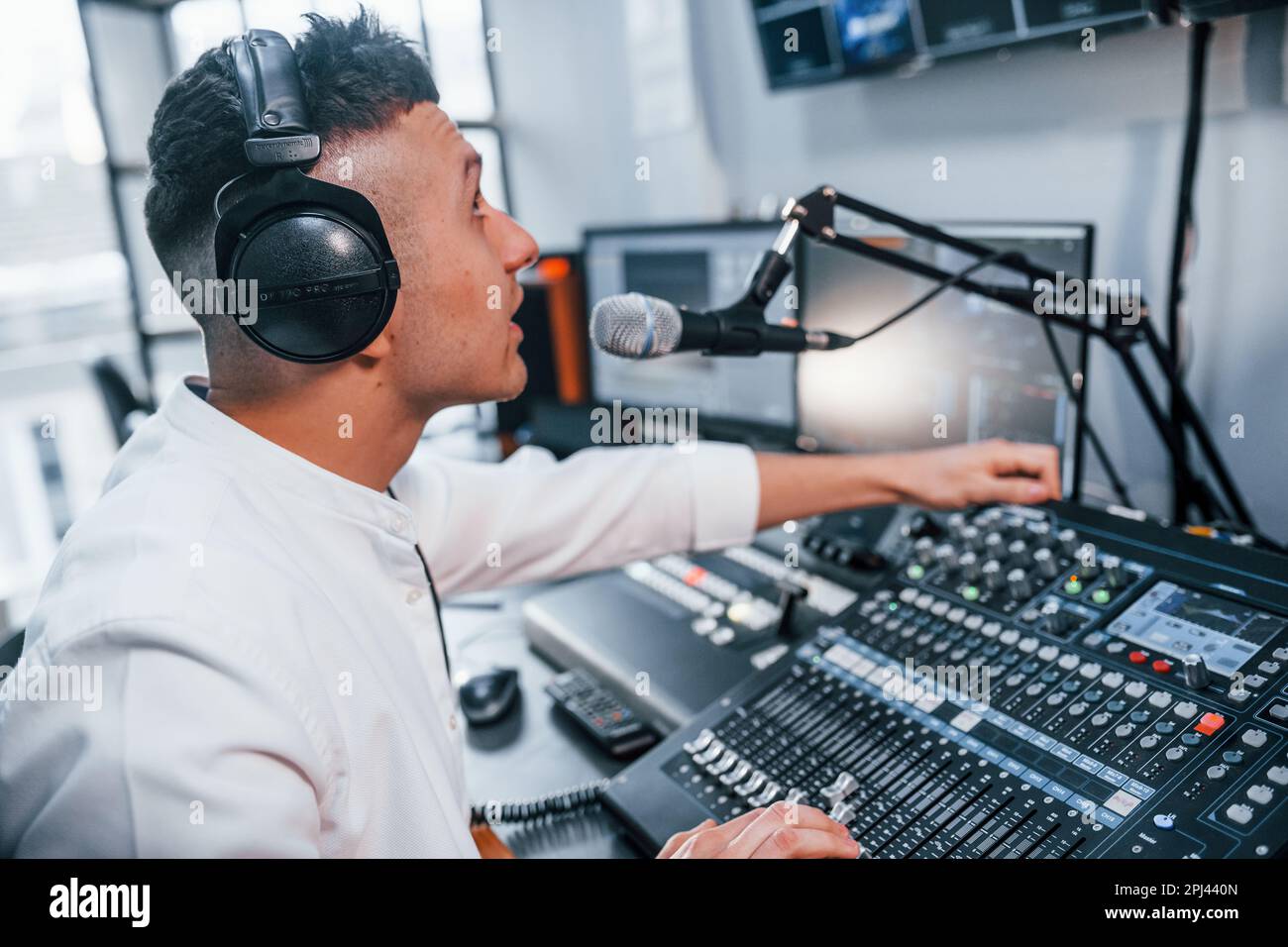Setting the equipment. Young man is indoors in the radio studio is busy ...