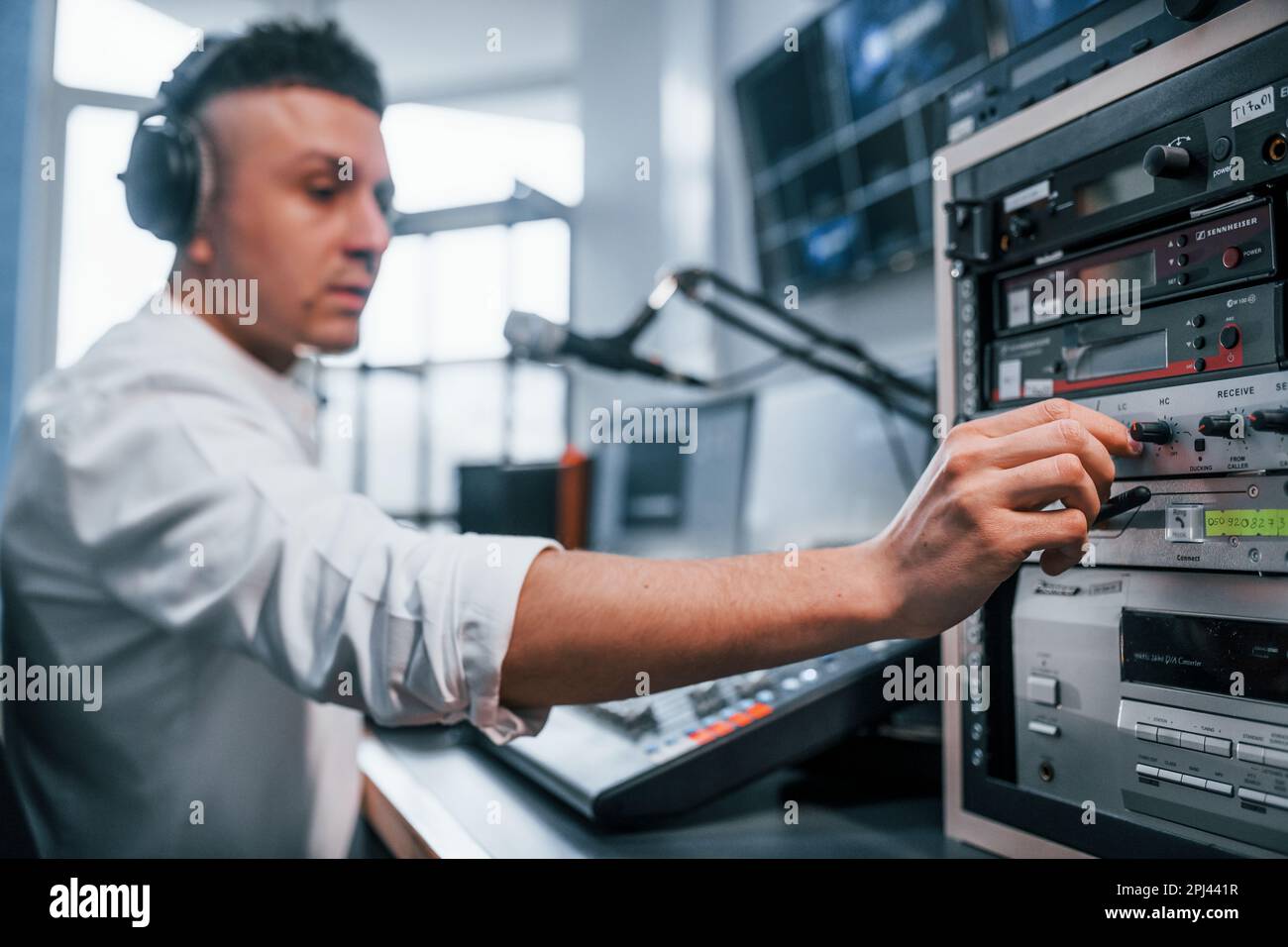 Setting the equipment. Young man is indoors in the radio studio is busy ...