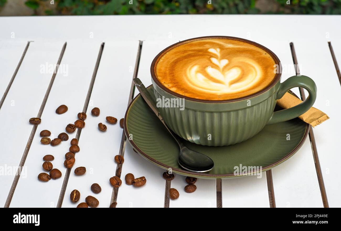Cup of cappuccino with spoon and sugar on wooden white table side view ...