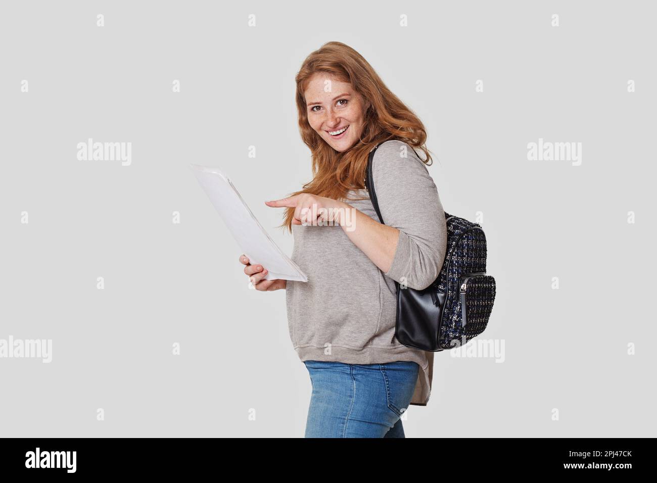 Happy woman pointing at documents on white studio background Stock ...