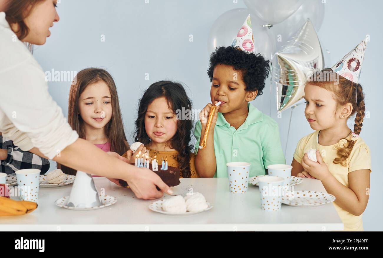 Woman holds cake. Children on celebrating birthday party indoors have ...