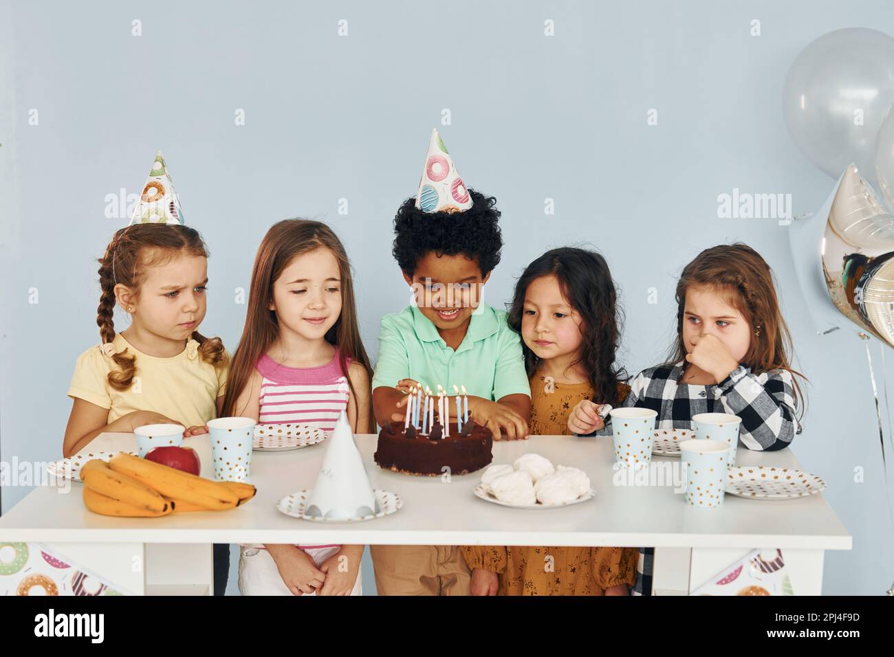 Sits by the table. Children on celebrating birthday party indoors have ...