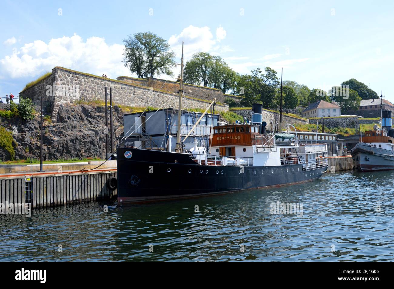 Norway, Oslo: a cargo ship moored under the walls of the Akershus ...