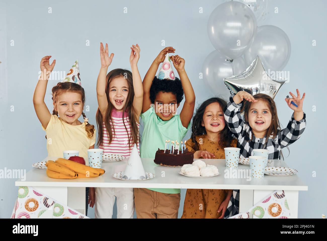 Sits by the table. Children on celebrating birthday party indoors have ...