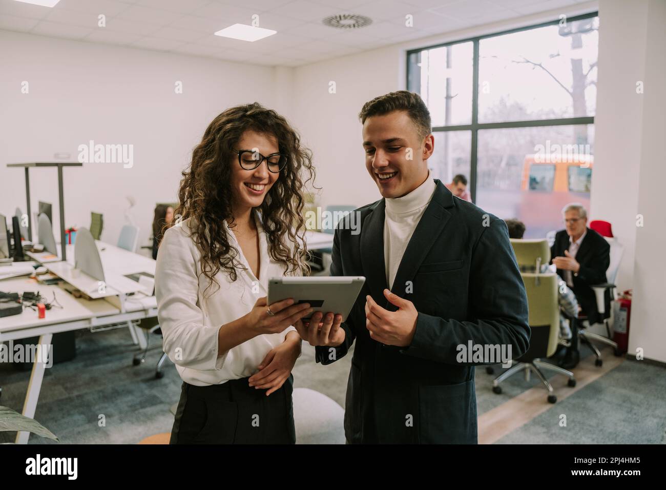 Two partners pointing a on the tablet and talking about something a the ...