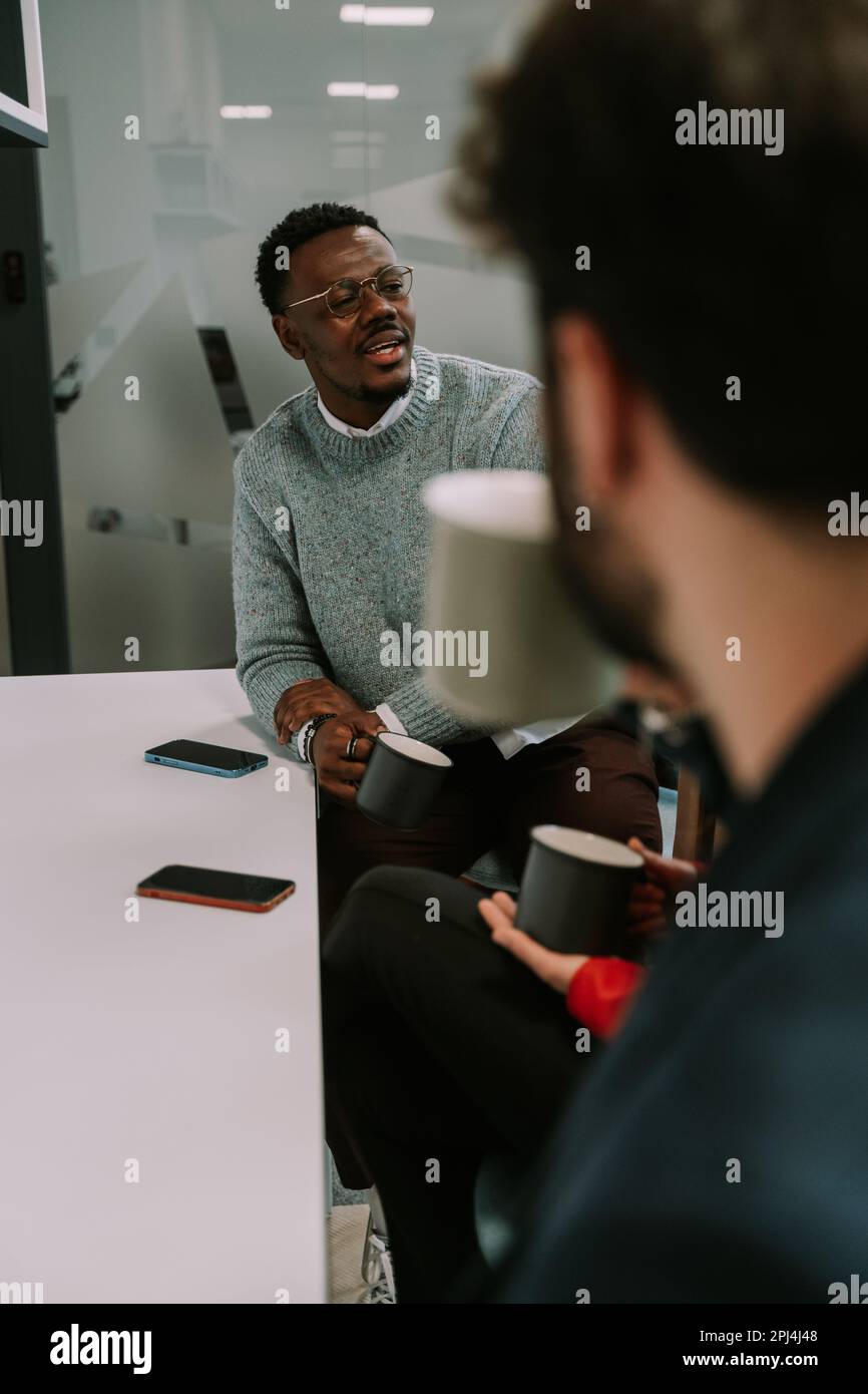 Good looking black male person talking to his colleagues Stock Photo ...