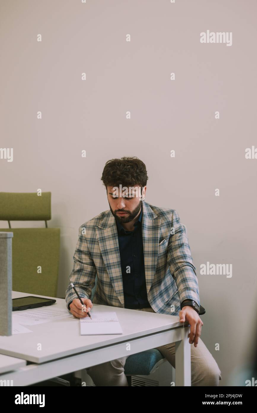Handsome business man writting notes in the notebook while sitting at ...