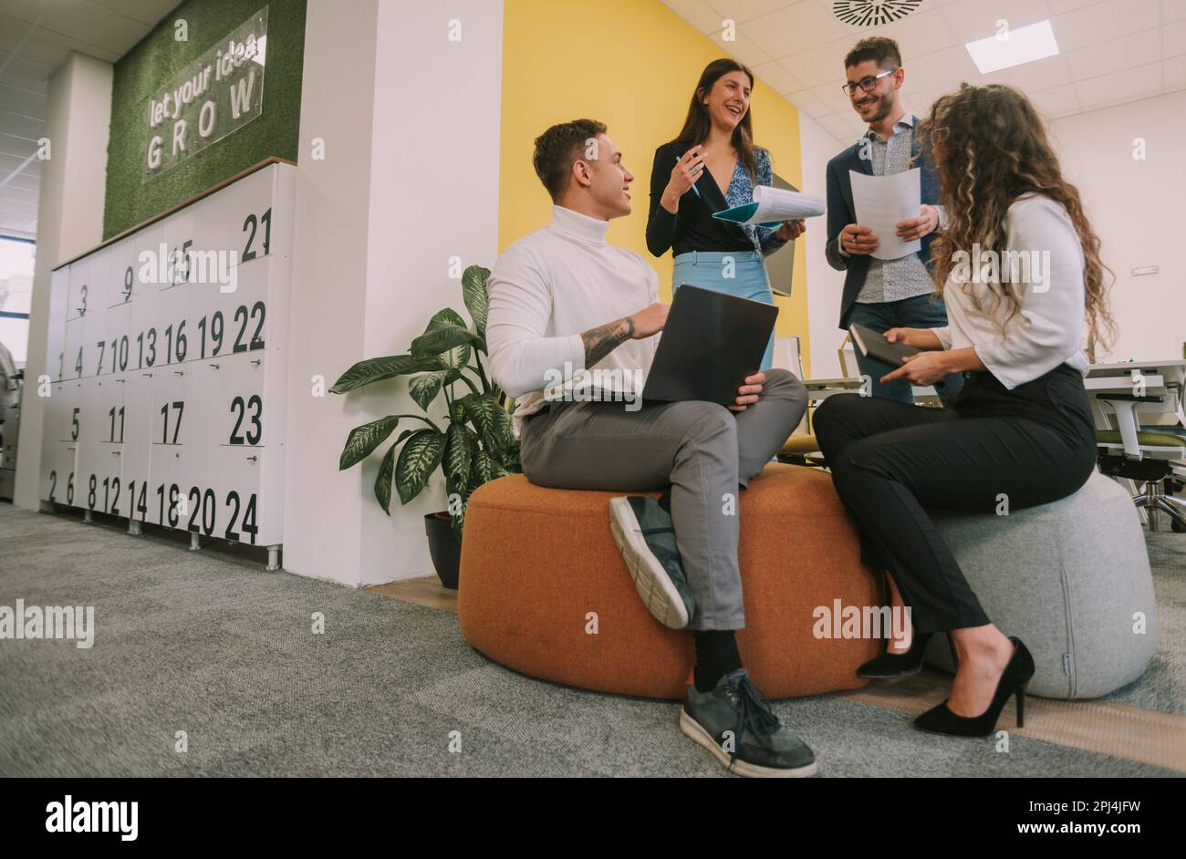 Four business people having conversation while two of them standing and ...