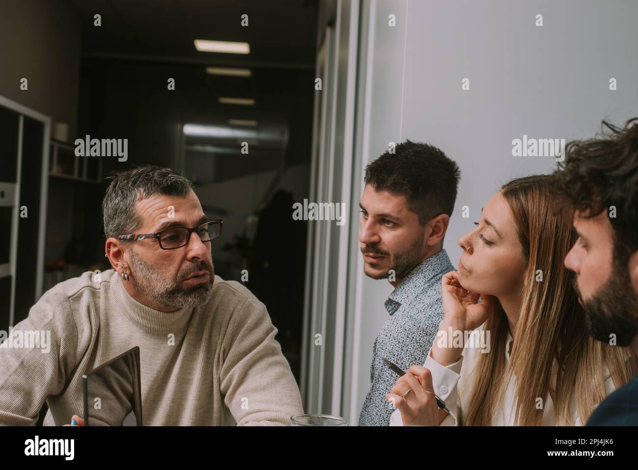 Four inter-generational group of business people discussing statistics ...