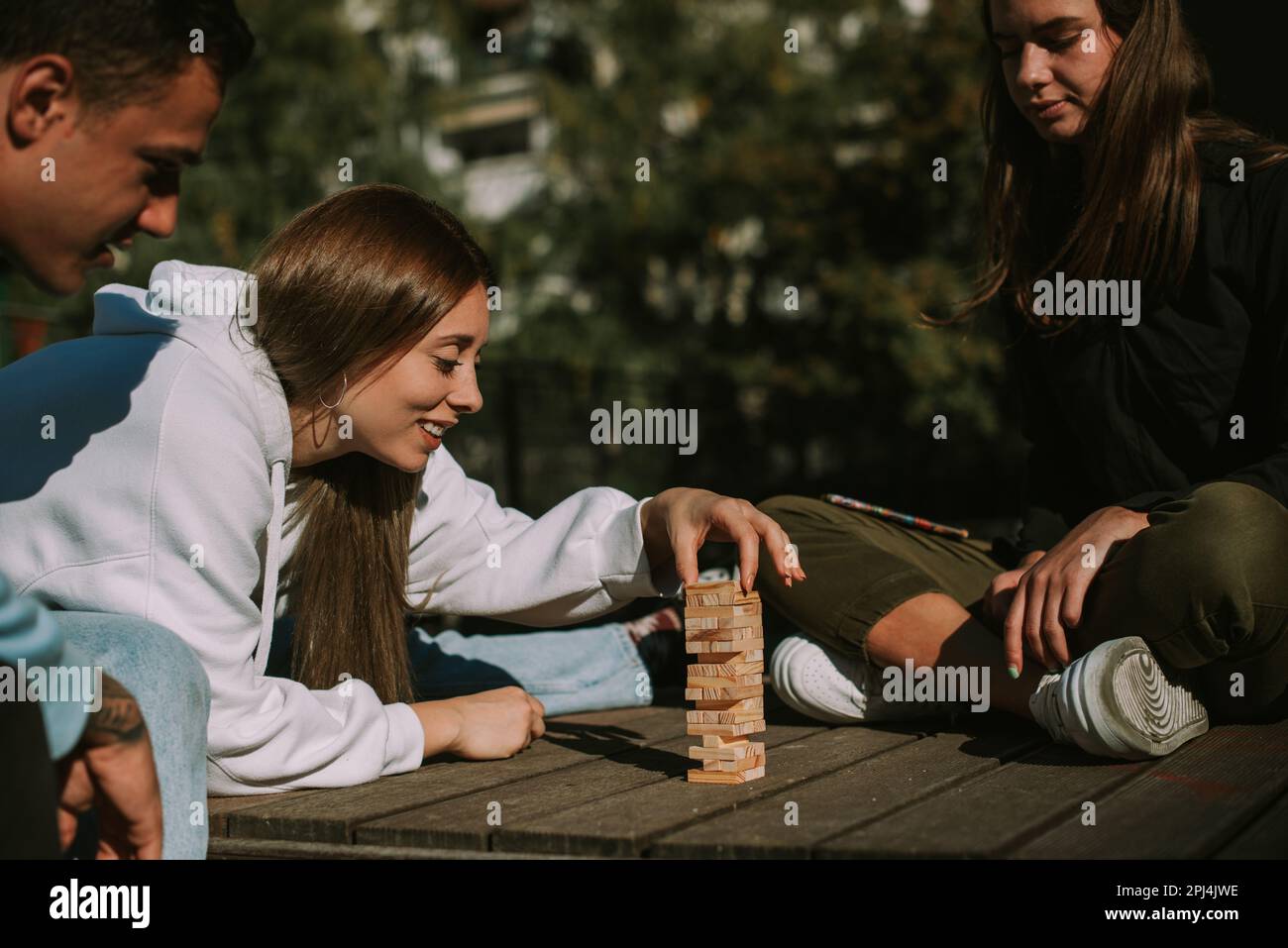 Close up of beautiful blonde girl playing jenga with her friends on the ...