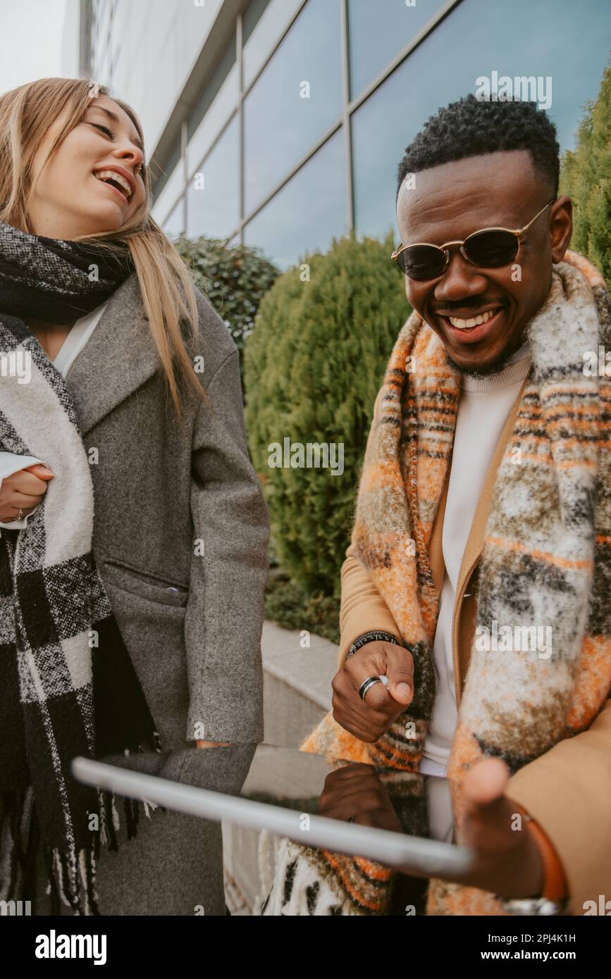 Two business colleagues laughing while working outside in front of the ...