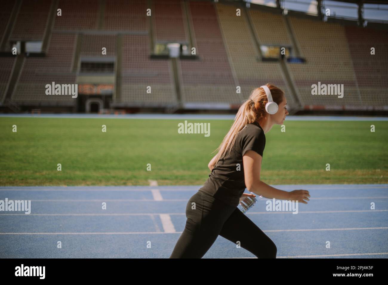 Pretty girl jogging around the stadium with headphones on Stock Photo ...