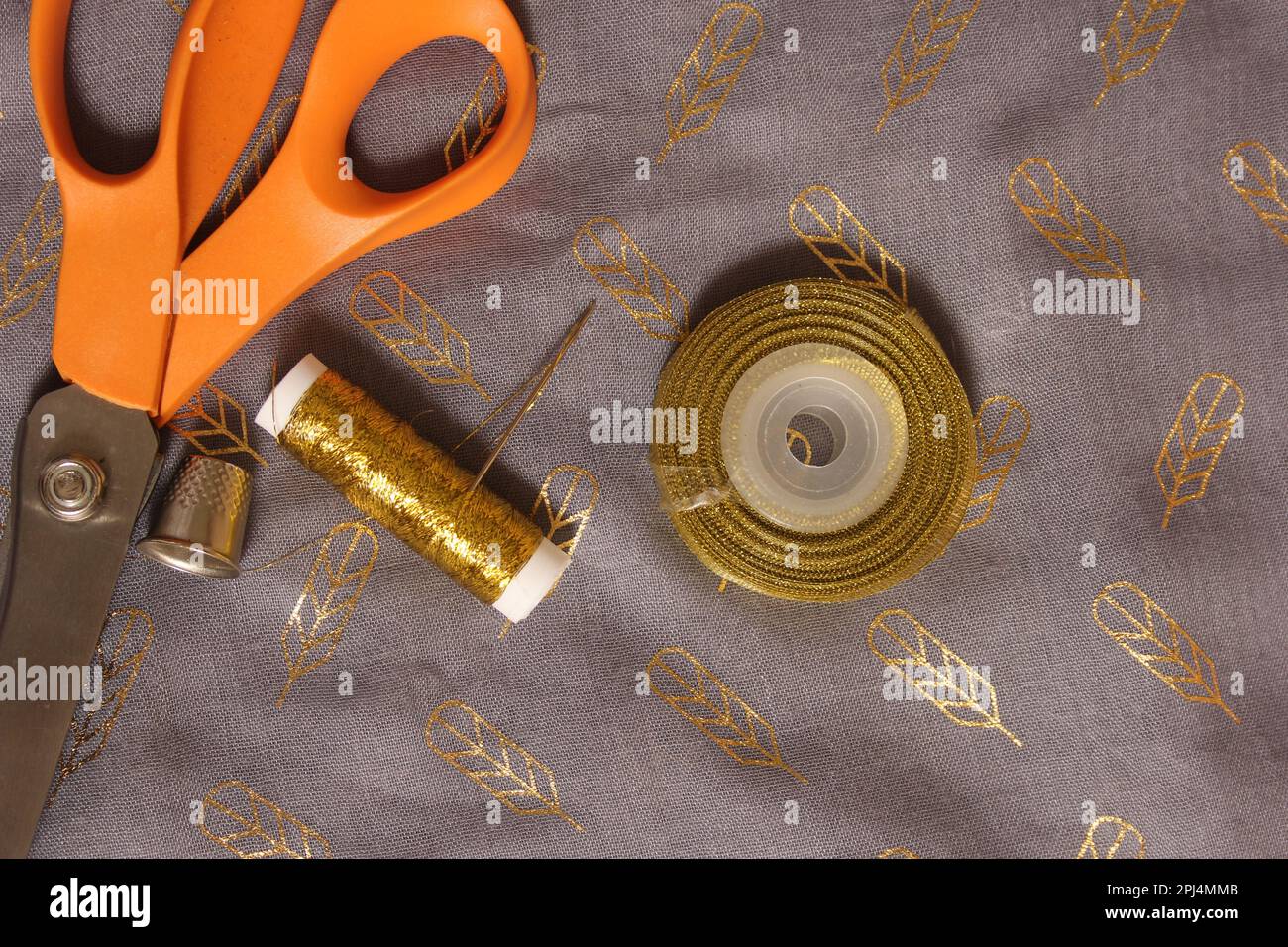 Spool of Metallic Gold Thread on Gray and Gold Fabric Stock Photo - Alamy