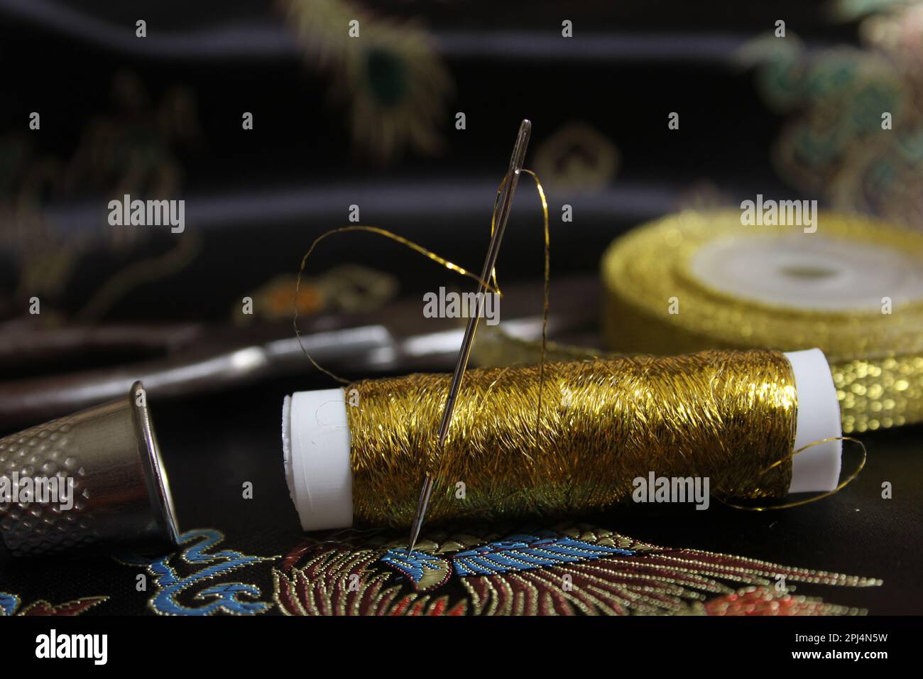 Spool of Gold Thread With Thimble on Black Asian Silk Fabric Stock ...