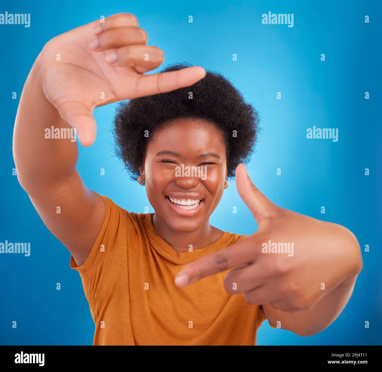 Finger framing, portrait and happy black woman on blue background ...