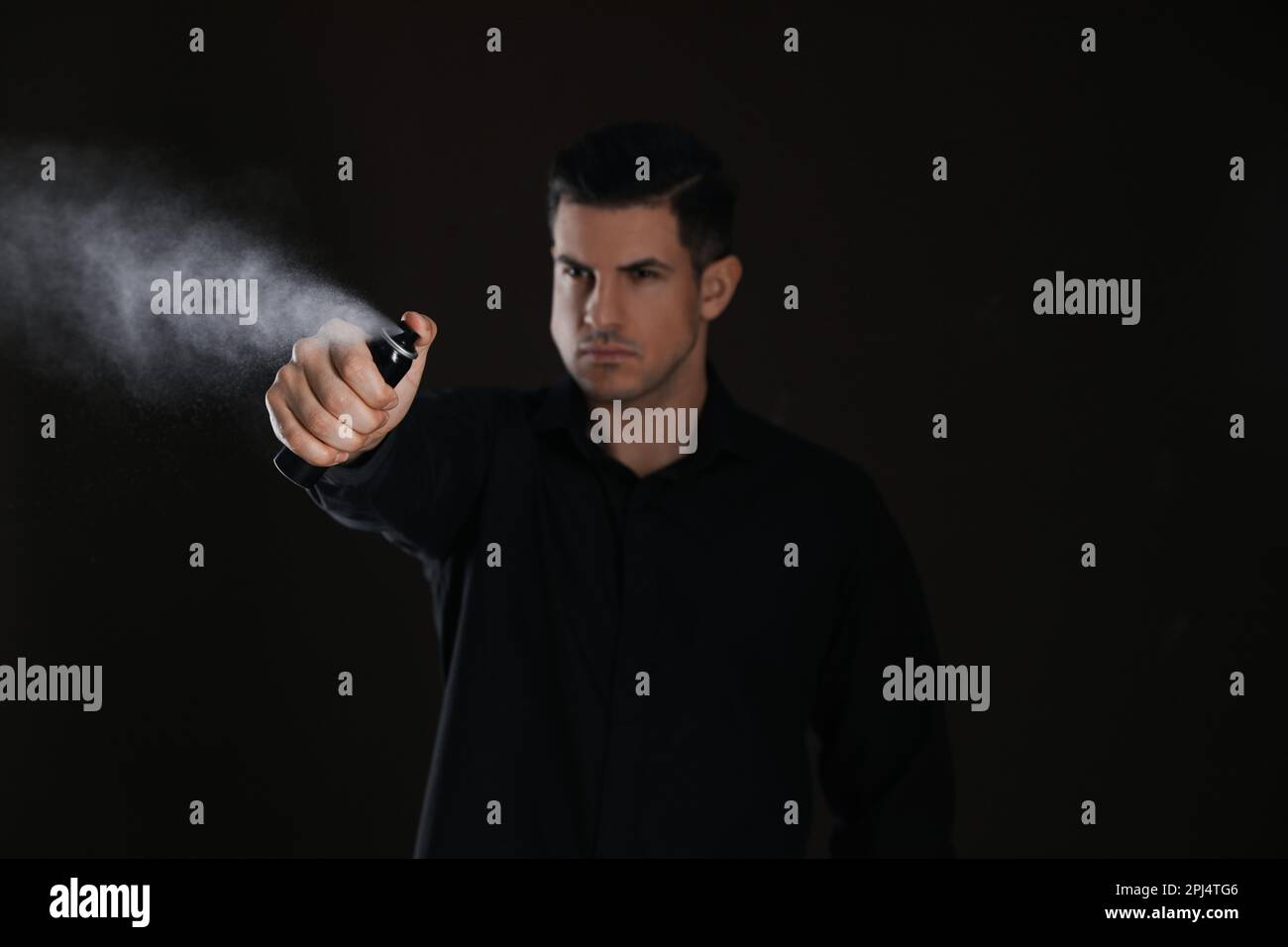 Man using pepper spray against black background, focus on hand Stock ...