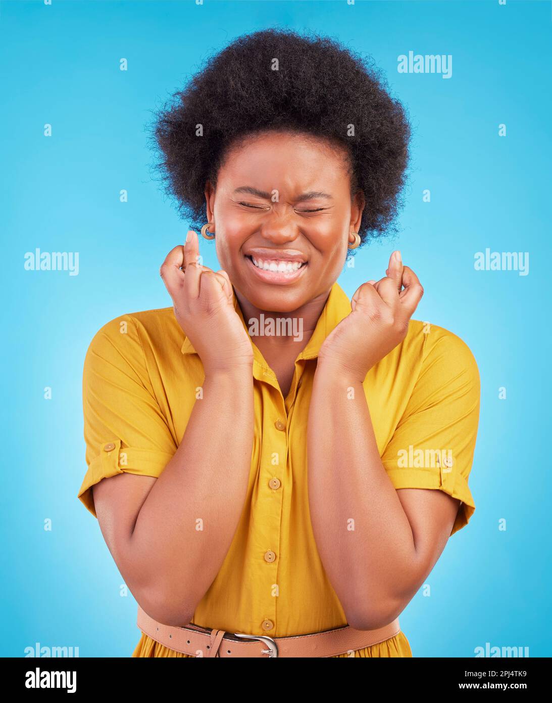Black woman, fingers crossed and hope in studio, blue background and ...