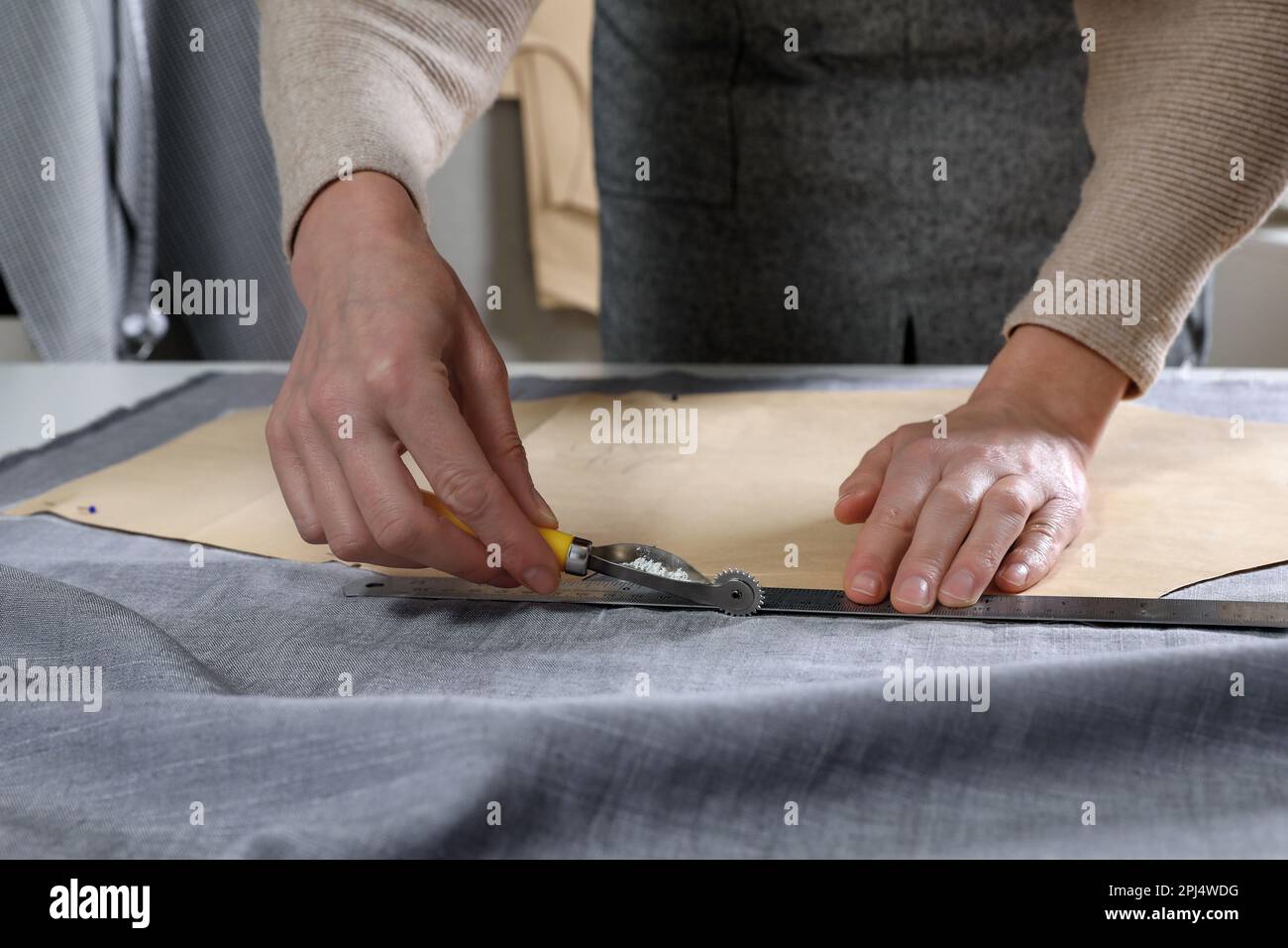 Tailor transferring sewing pattern onto fabric with tracing wheel in ...