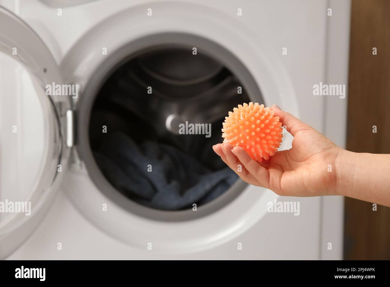 Woman putting dryer ball into washing machine, closeup Stock Photo - Alamy