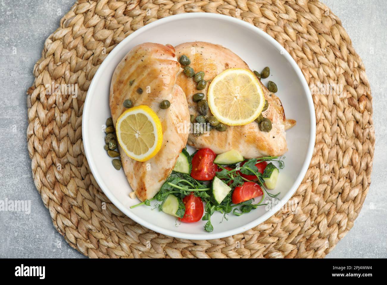 Delicious cooked chicken fillets with capers and salad on light grey ...
