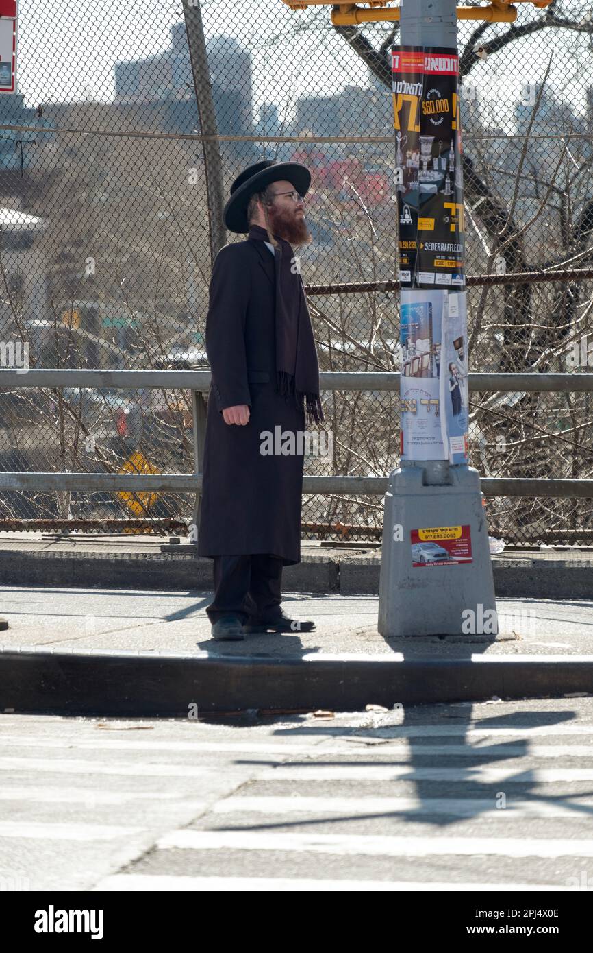 An orthodox Jewish man dressed in black reads posters & announcements ...