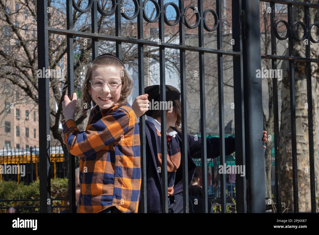 A Hasidic jews boy enjoys swinging on a fence door during recess from ...