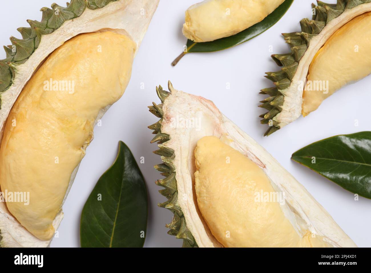 Pieces of fresh ripe durian and leaves on white background, flat lay ...