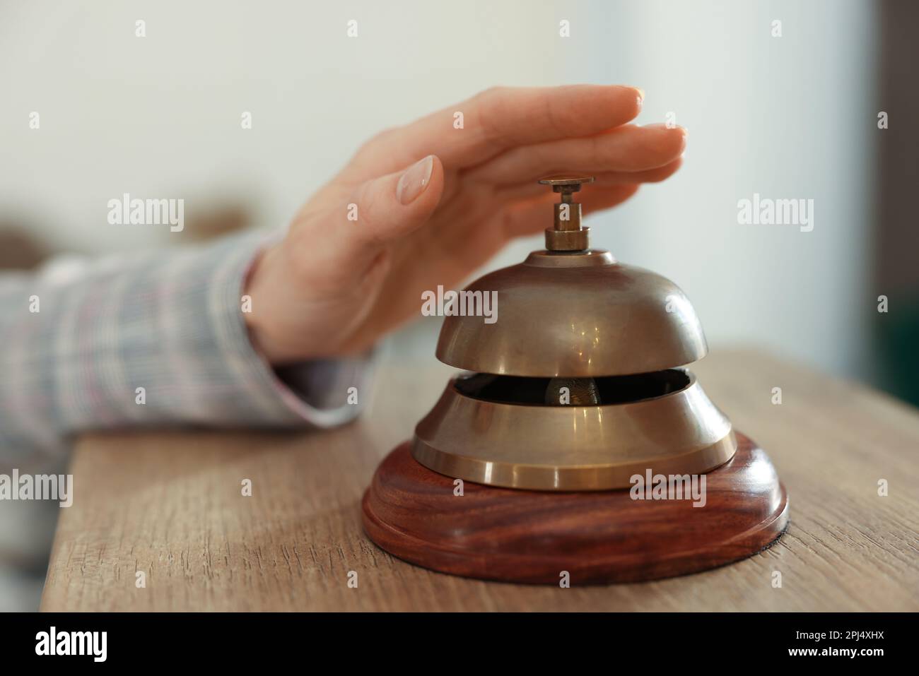 Woman ringing hotel service bell at wooden reception desk, closeup ...