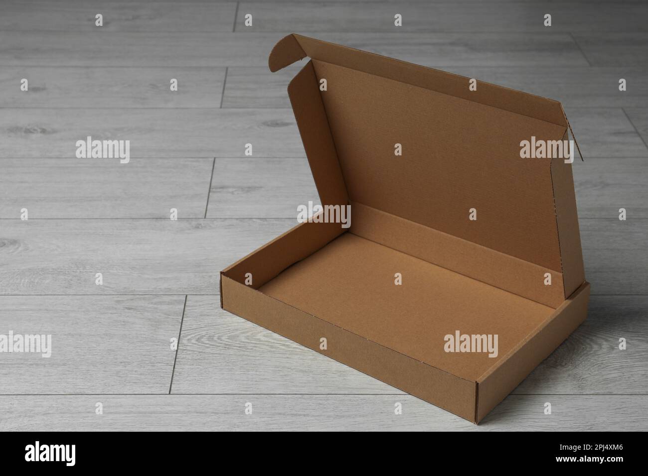 Empty open cardboard box on floor, space for text Stock Photo - Alamy