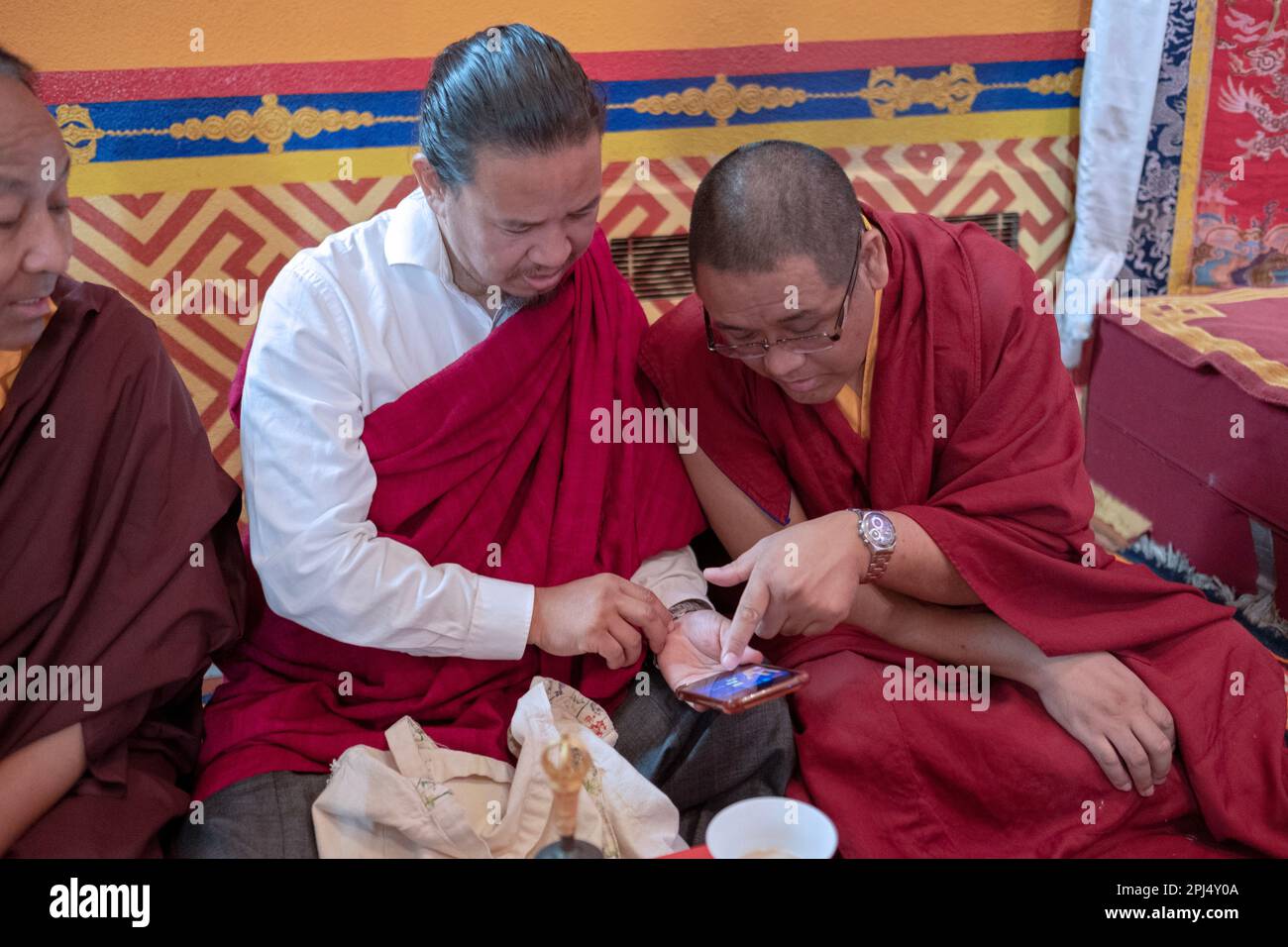 Technology & Tradition. Buddhist monks in their burgundy robes check ...