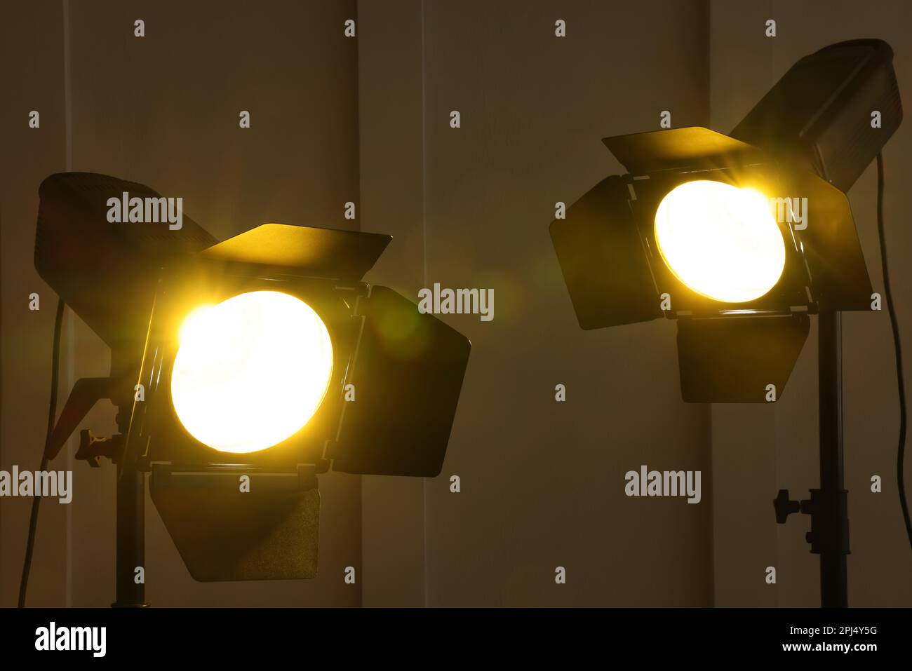 Bright yellow spotlights near wall indoors. Professional stage ...