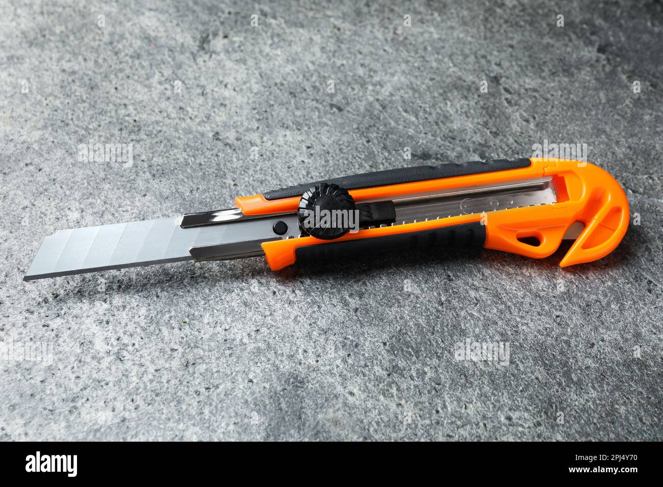 Orange utility knife on grey table. Construction tool Stock Photo - Alamy