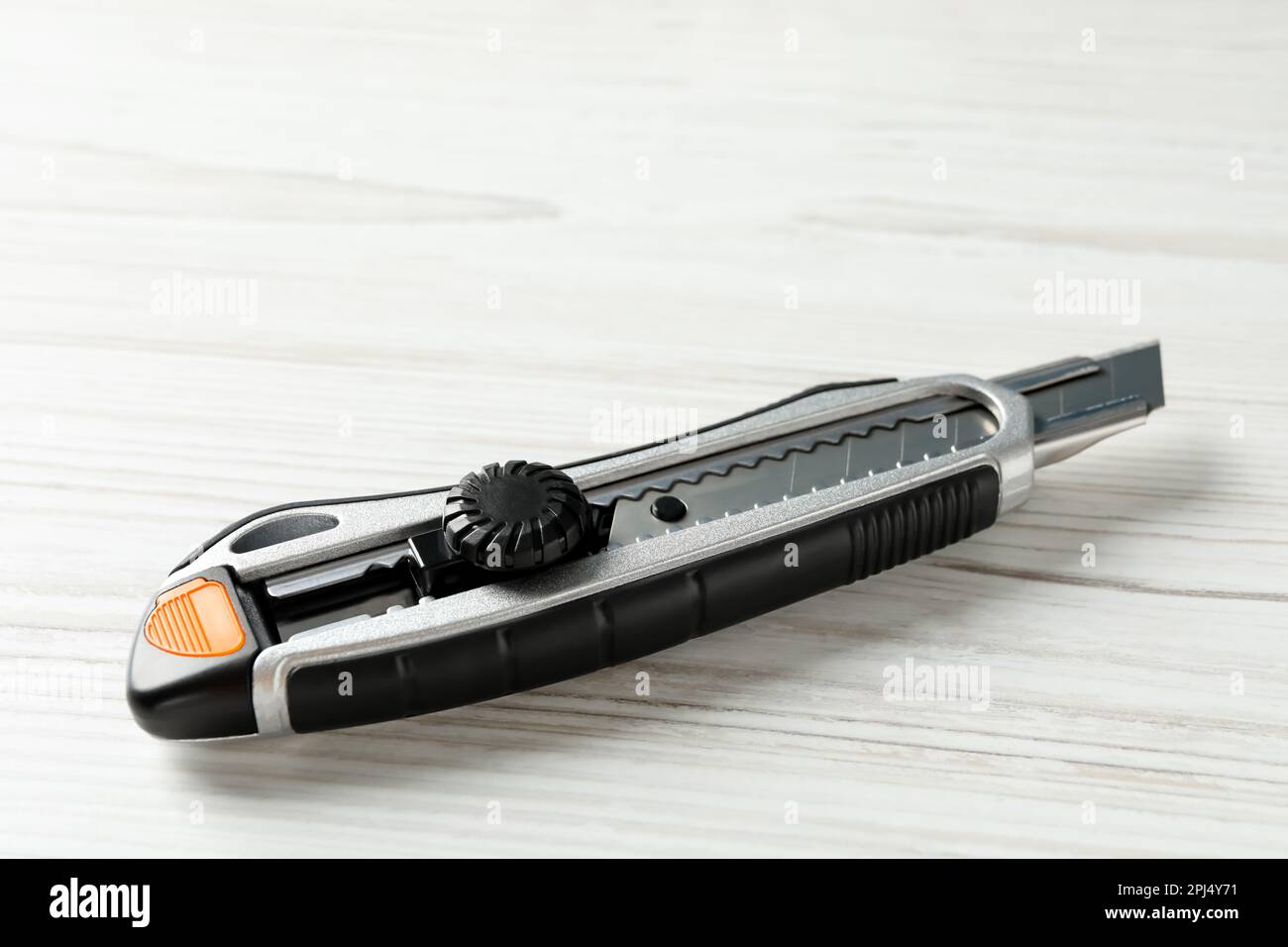 Utility knife on white wooden table. Construction tool Stock Photo - Alamy
